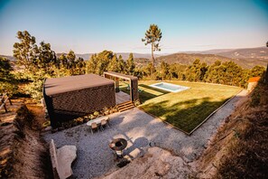 Um quintal com piscina, área de churrasco e espaço para sentar.