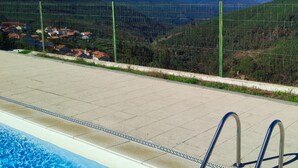 Piscina com vista para montanhas e casas ao fundo.
