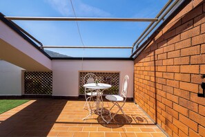 Um pátio com mesa e cadeiras, um muro de tijolos e um céu azul claro.