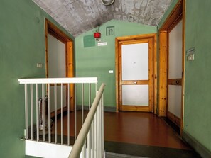 Um corredor com paredes verdes, portas de madeira e corrimão branco.