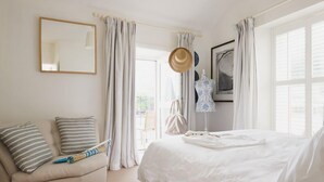 Quarto com cama, sofá e janela.