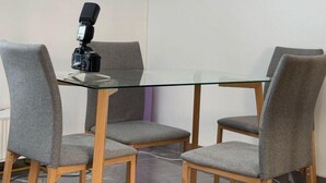 Uma sala de jantar moderna com mesa de vidro e cadeiras de madeira.