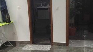 Quarto com sofá, porta para banheiro e planta em vaso.