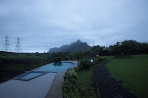 Uma piscina com vista para uma montanha e linhas de eletricidade ao fundo.