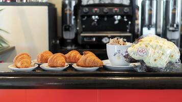 Croissants em pratos e uma tigela de café sobre um balcão.
