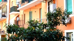 Um edifício com vários andares, varandas, persianas verdes e aparelhos de ar condicionado.
