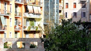 Um edifício residencial com vários andares e varandas, algumas com plantas.