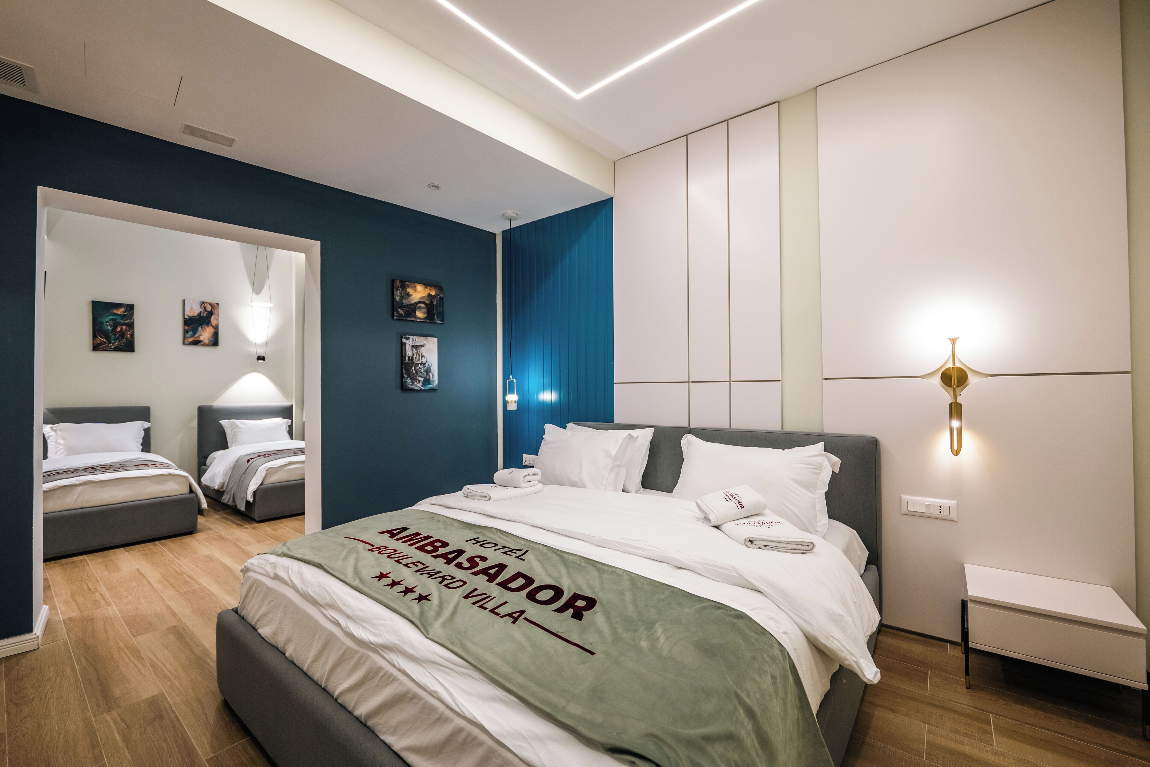 Quarto de hotel com uma cama grande, mesas de cabeceira, um espelho e obras de arte nas paredes.