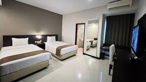 Quarto de hotel com duas camas, uma escrivaninha, uma televisão e um espelho.