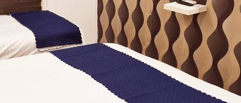 Quarto de hotel com duas camas, televisão e ar condicionado fixado na parede.