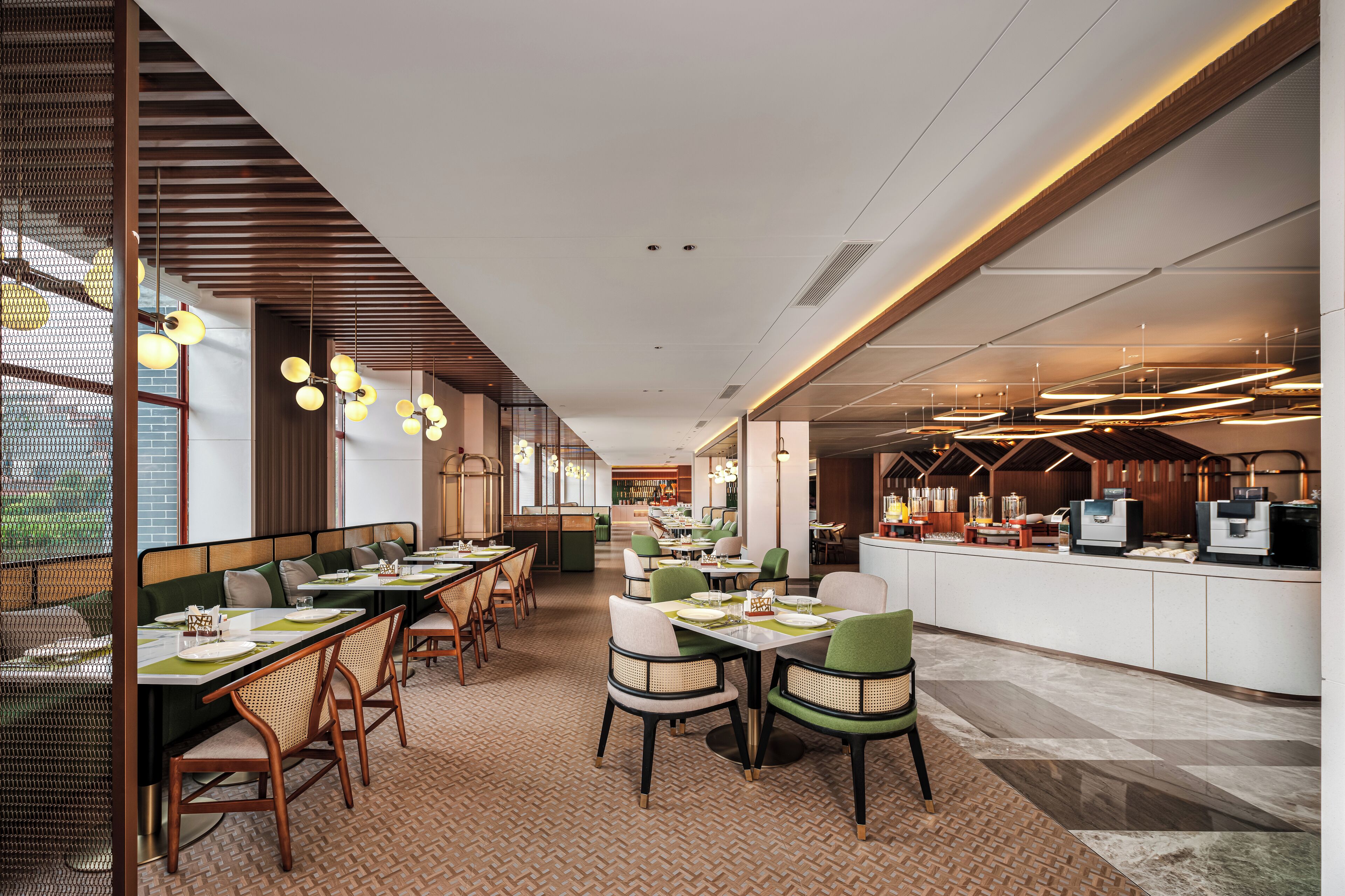 Um restaurante moderno com mesas altas, cadeiras verdes e um balcão comprido com uma máquina de café.