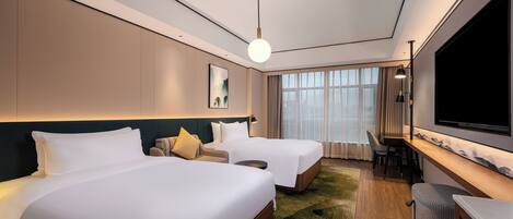 Quarto de hotel moderno com duas camas, uma escrivaninha, uma cadeira e uma televisão grande.