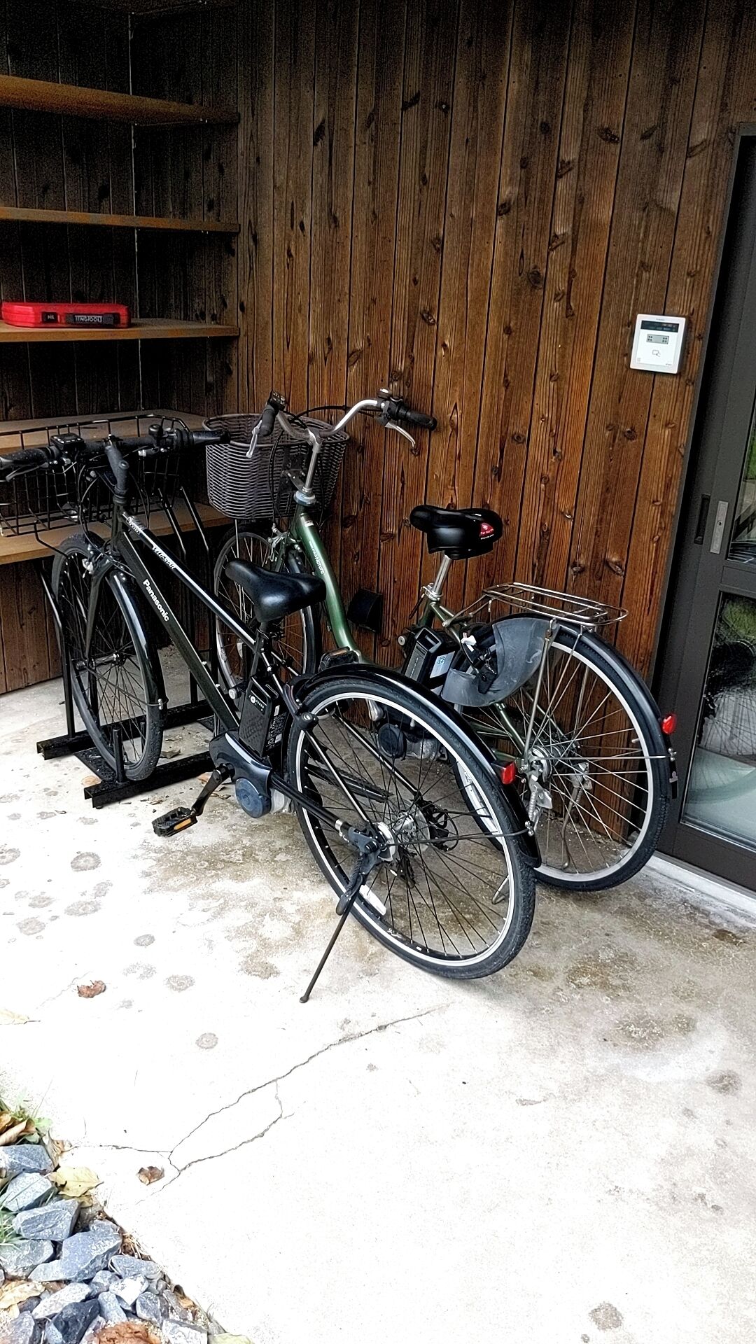 Uma bicicleta com cesto e bagageiro encostada a uma parede de madeira.