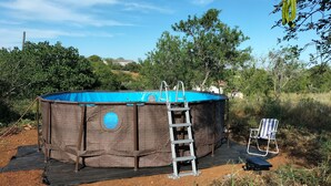 Piscina retangular com interior azul, rodeada por uma cerca marrom e uma escada de acesso.