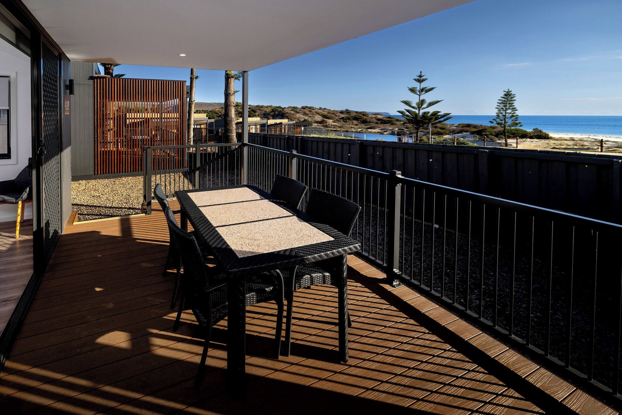 Varanda com mesa e cadeiras, com vista para a praia e oceano.