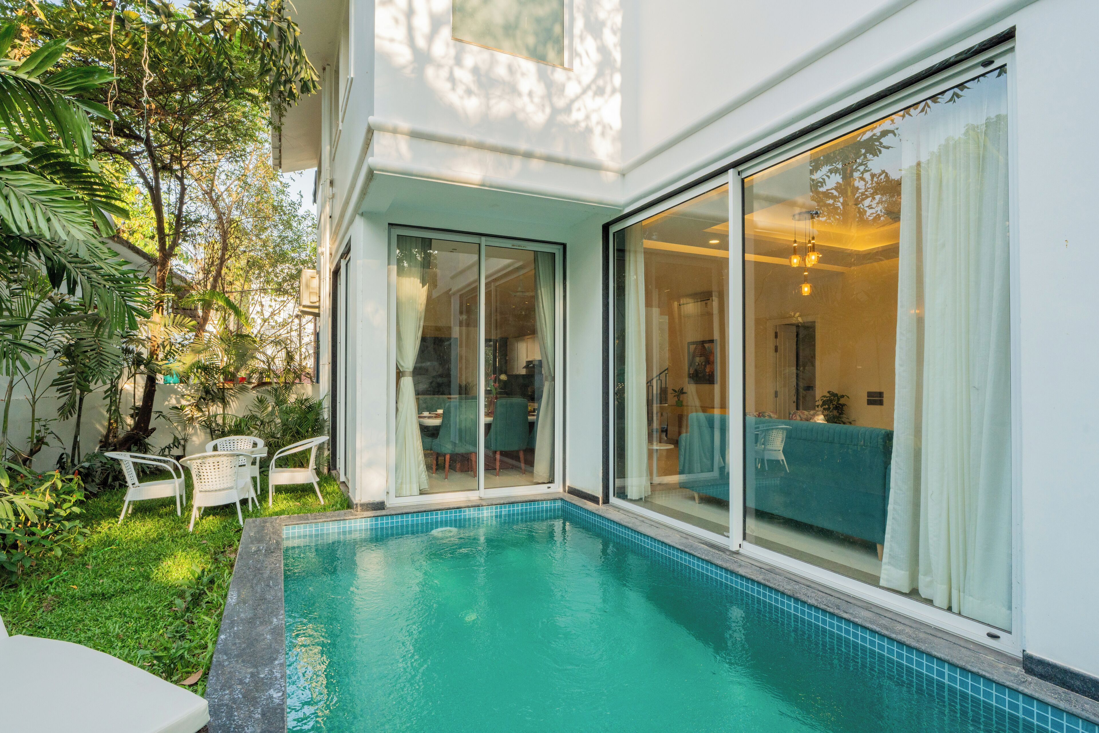 Uma casa moderna com piscina, portas de vidro deslizantes e um gramado verde.