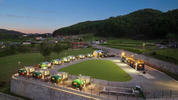 Um camping com tendas verdes e uma estrada pavimentada.