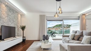 Uma sala de estar moderna com uma TV de tela plana, uma mesa de centro de vidro e um sofá.