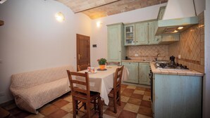 Uma cozinha acolhedora com mesa de jantar, cadeiras de madeira, sofá e fogão a gás.