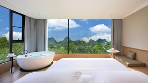 Quarto de hotel moderno com uma cama grande, uma banheira e vista para as montanhas.