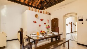 Uma sala de jantar com uma mesa de madeira posta para quatro pessoas, um banco e uma parede decorada com peixes e estrelas-do-mar.