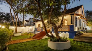 Um jardim bem cuidado com um caminho pavimentado que leva a um edifício com telhado telhado e uma varanda.