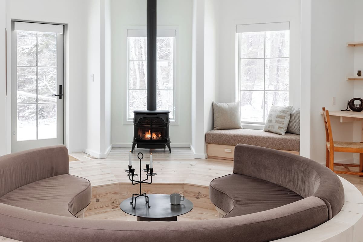 Uma sala de estar moderna com uma área de estar circular, uma mesa de centro e uma lareira.