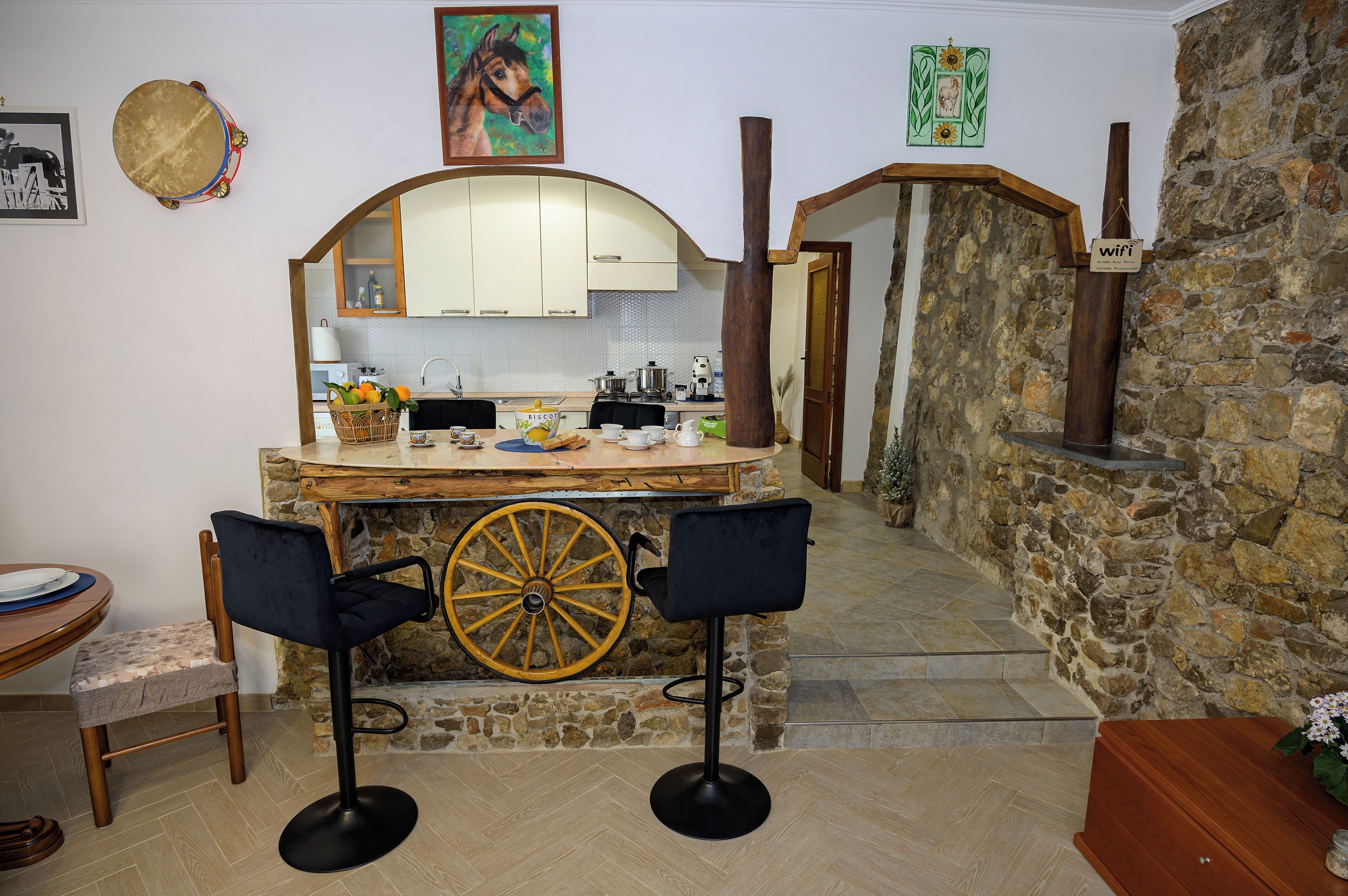 Uma cozinha com parede de pedra, balcão de madeira e um carrinho de mão rústico.
