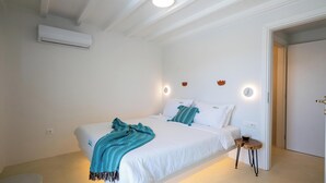 Quarto com cama, mesa de cabeceira, luminária na parede e aparelho de ar condicionado.