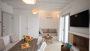 Uma sala de estar moderna com uma mesa de jantar de madeira, cadeiras brancas, um sofá e uma lareira.