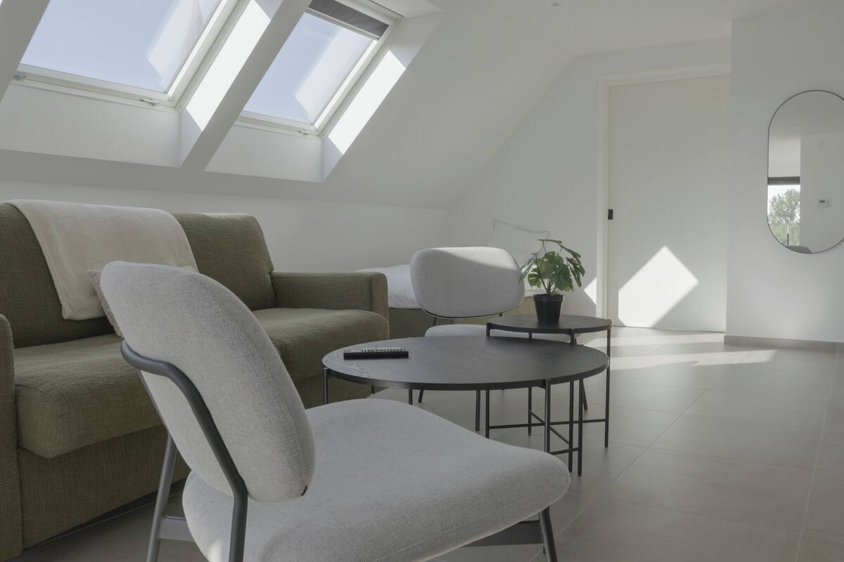 Uma sala de estar moderna com sofá, poltronas, uma mesinha e um vaso de planta.