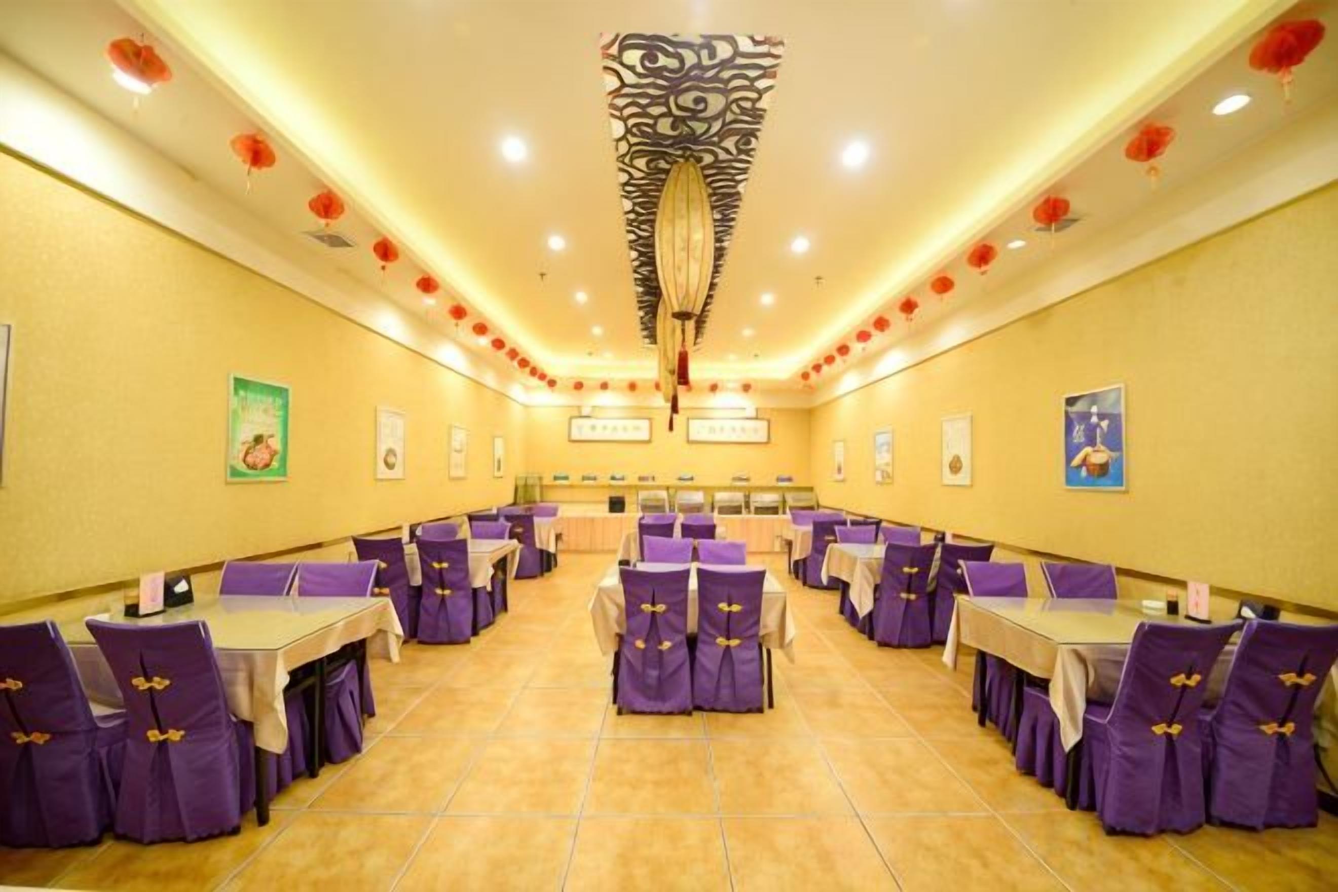 Uma sala de banquetes com várias mesas e cadeiras, um corredor central e teto decorativo.