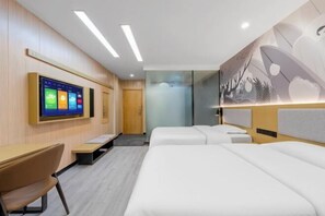 Quarto de hotel moderno com uma grande TV de tela plana na parede, uma escrivaninha com cadeira, duas camas e um grande mural abstrato na parede.