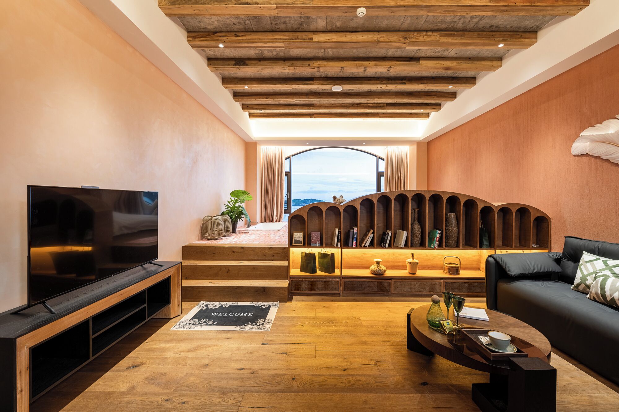 Uma sala de estar moderna com televisão, sofá, mesa de centro e estante de livros.