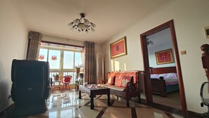 Uma sala de estar ampla, com uma janela grande, um sofá, uma mesa de centro e uma poltrona.