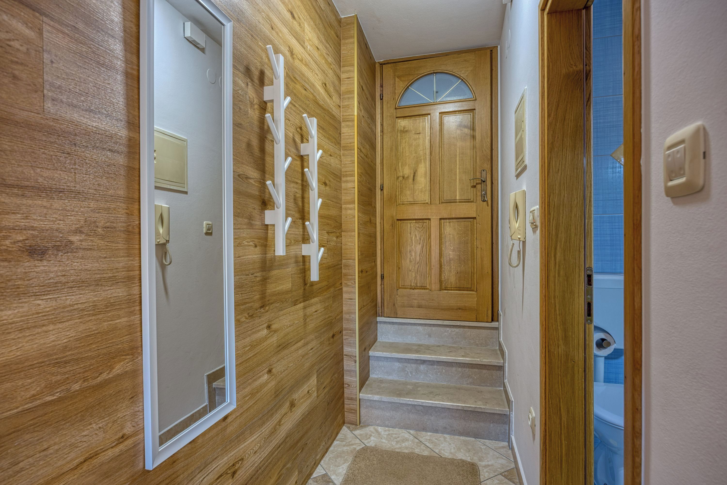 Um corredor de madeira com uma porta que dá para um banheiro.