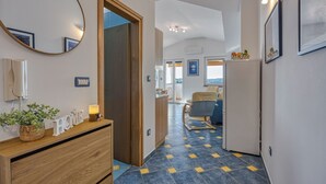 Corredor de hotel com cômoda de madeira, um espelho e uma cama ao fundo.