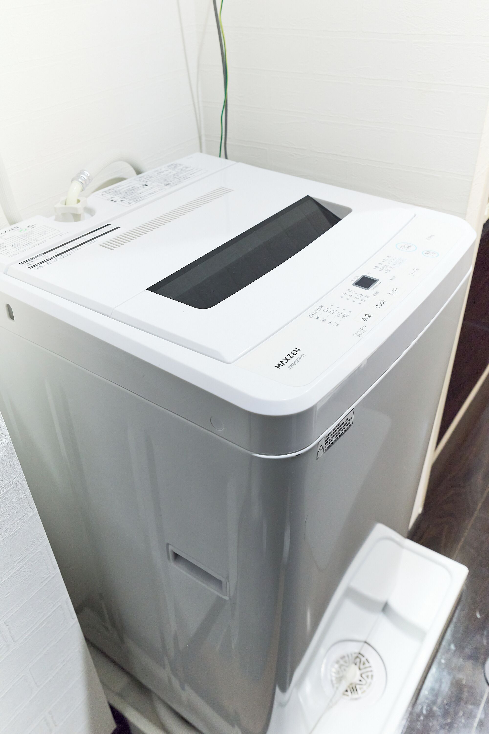 Máquina de lavar compacta e moderna, com painel de controle, compartimento de armazenamento pequeno e cabo de alimentação.