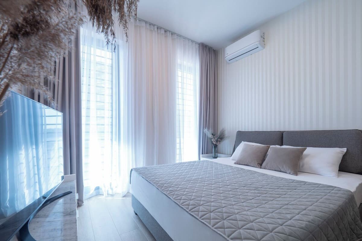 Um quarto moderno com uma cama grande, uma TV de tela plana e um ar-condicionado na parede.