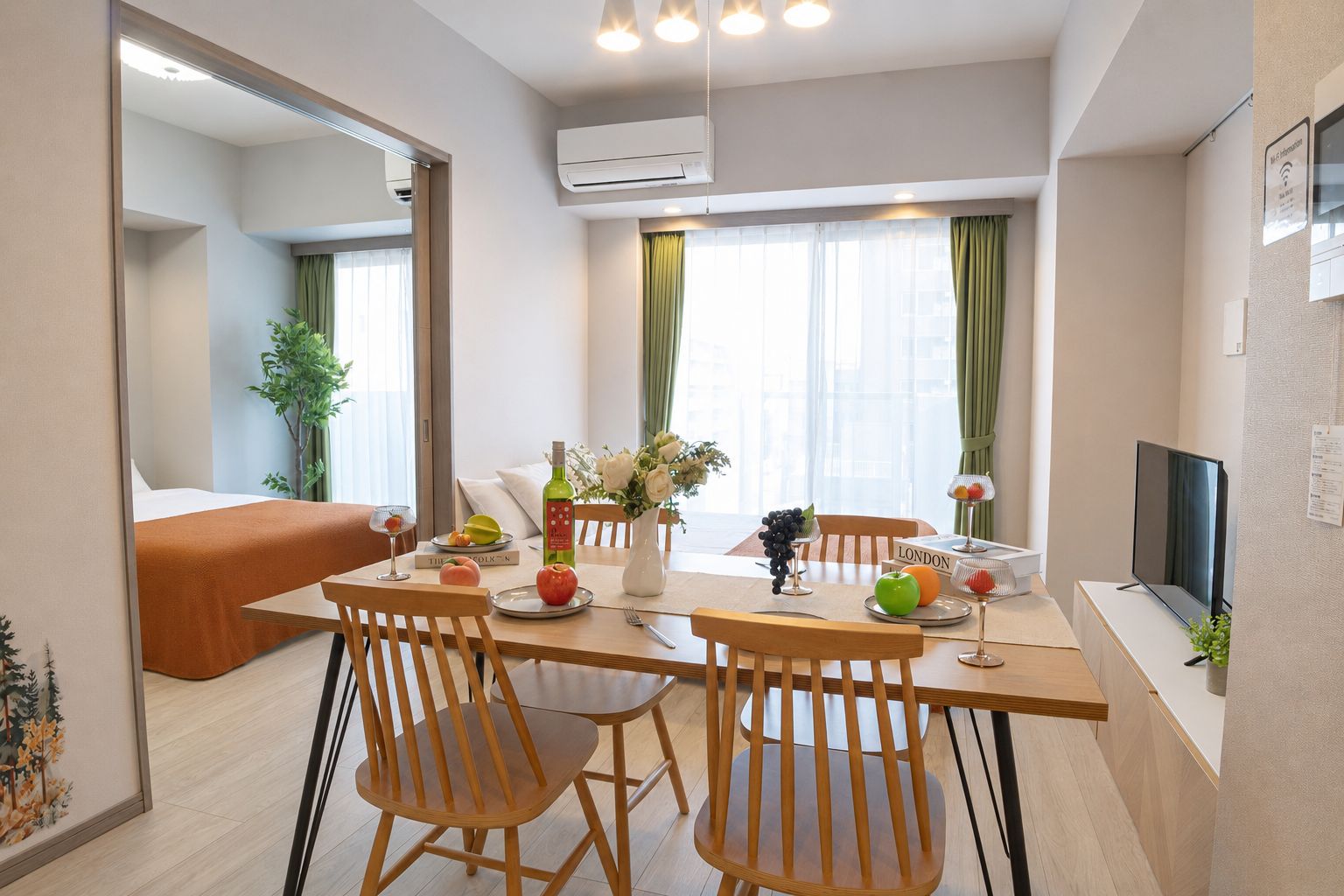 Quarto de hotel moderno com área de jantar, cama, televisão e janela com cortinas.