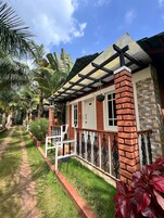 Uma pequena casa com fachada de tijolos, uma parede de pedra e telhado de metal.