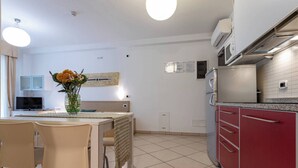Cozinha moderna com área de jantar, incluindo uma mesa com cadeiras, um vaso de flores e um micro-ondas.