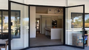 Uma casa moderna com porta de vidro que dá acesso a uma sala de estar com cozinha e espaço para refeições.