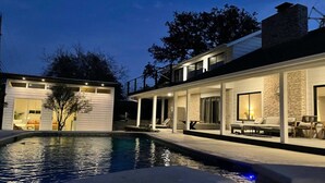 Uma casa moderna com piscina, varanda coberta e lareira de pedra.