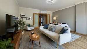 Uma sala de estar moderna com sofá, poltrona, mesa de centro e televisão.