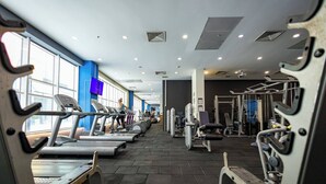 Uma academia com esteiras, aparelhos de musculação e equipamentos de ginástica.