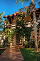 Um edifício de dois andares com fachada e varanda de madeira, e um caminho que leva à entrada.