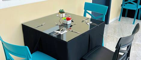 Uma sala de conferências com mesa de vidro, cadeiras azul-turquesa e toalha de mesa preta.