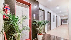 Corredor com plantas em vasos, um extintor de incêndio e uma porta com teclado de segurança.