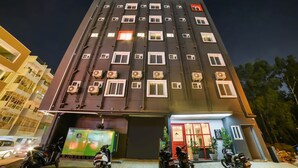 Um edifício de vários andares com aparelhos de ar condicionado, entrada no nível da rua e motocicletas estacionadas.